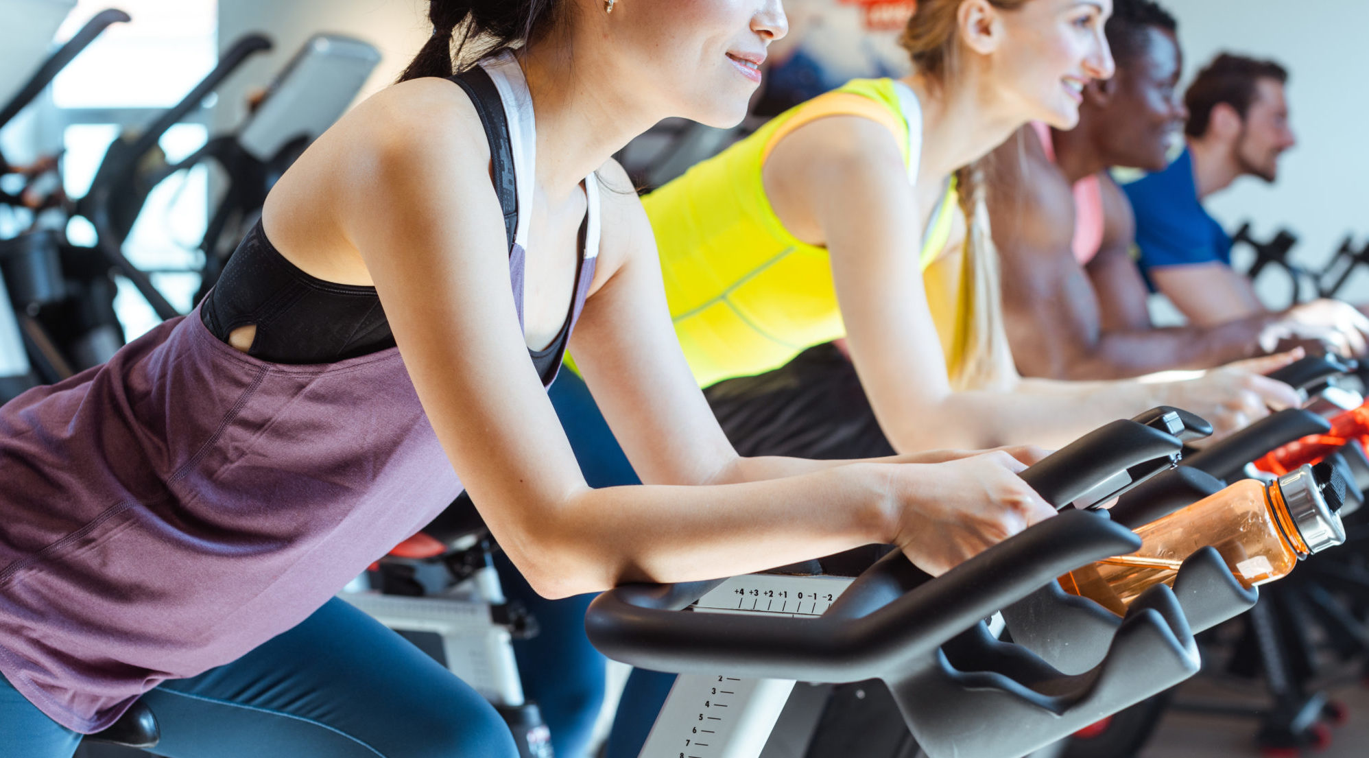 Asian woman and her friends on fitness bike in gym - TruSelf Sporting Club